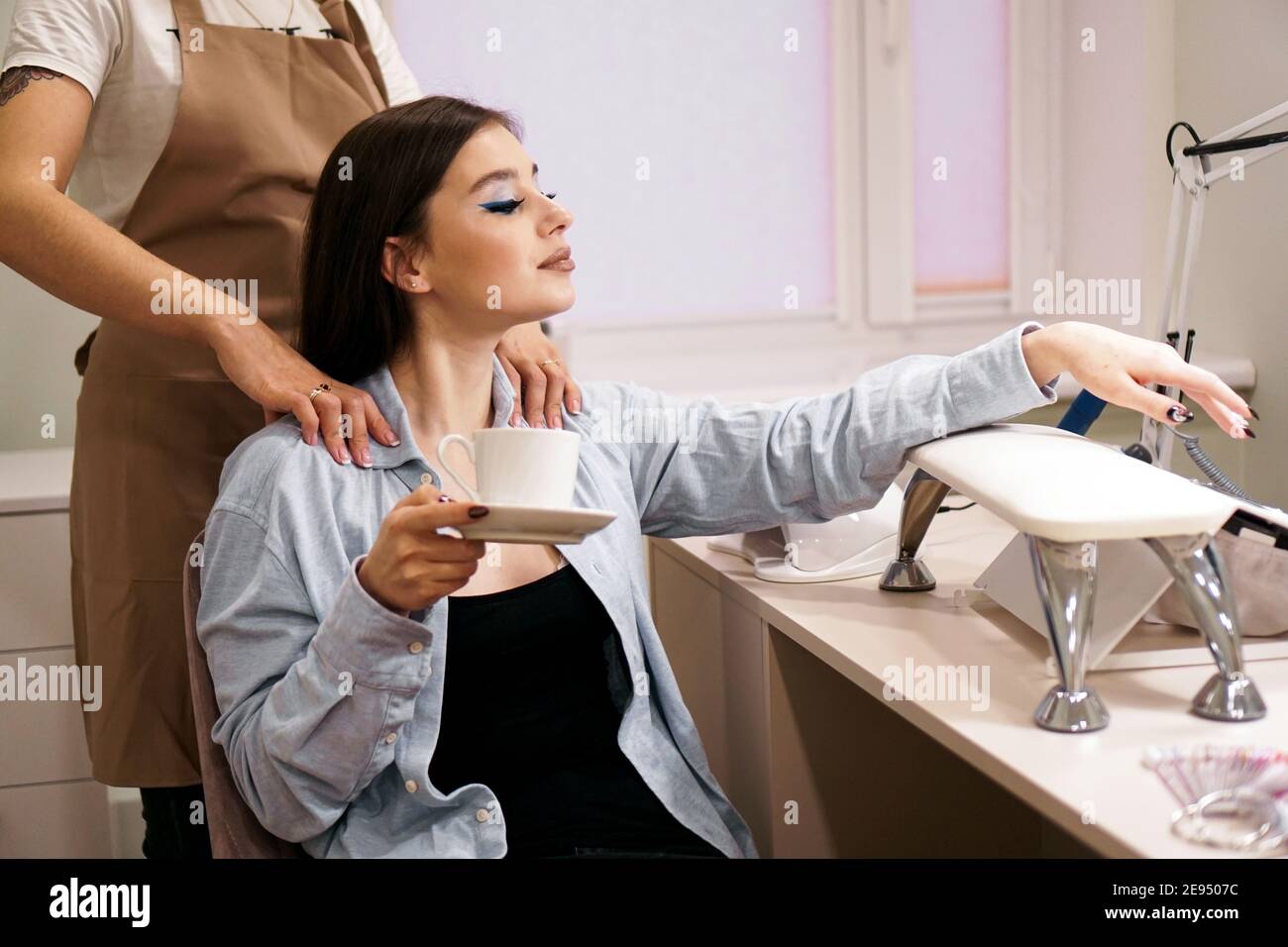 Beautiful woman getting manicure and massage at the same time in a ...