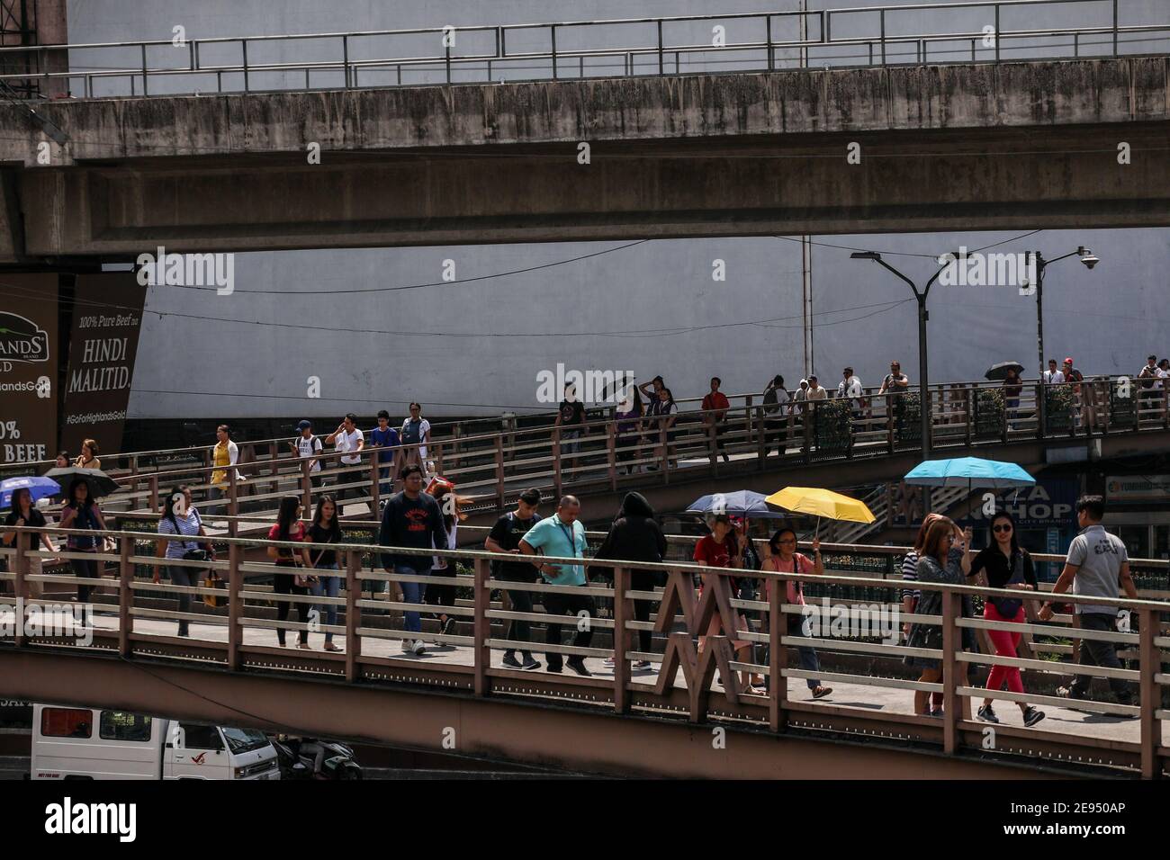 People walk on a pedestrian bridge along a major road. The Philippine ...