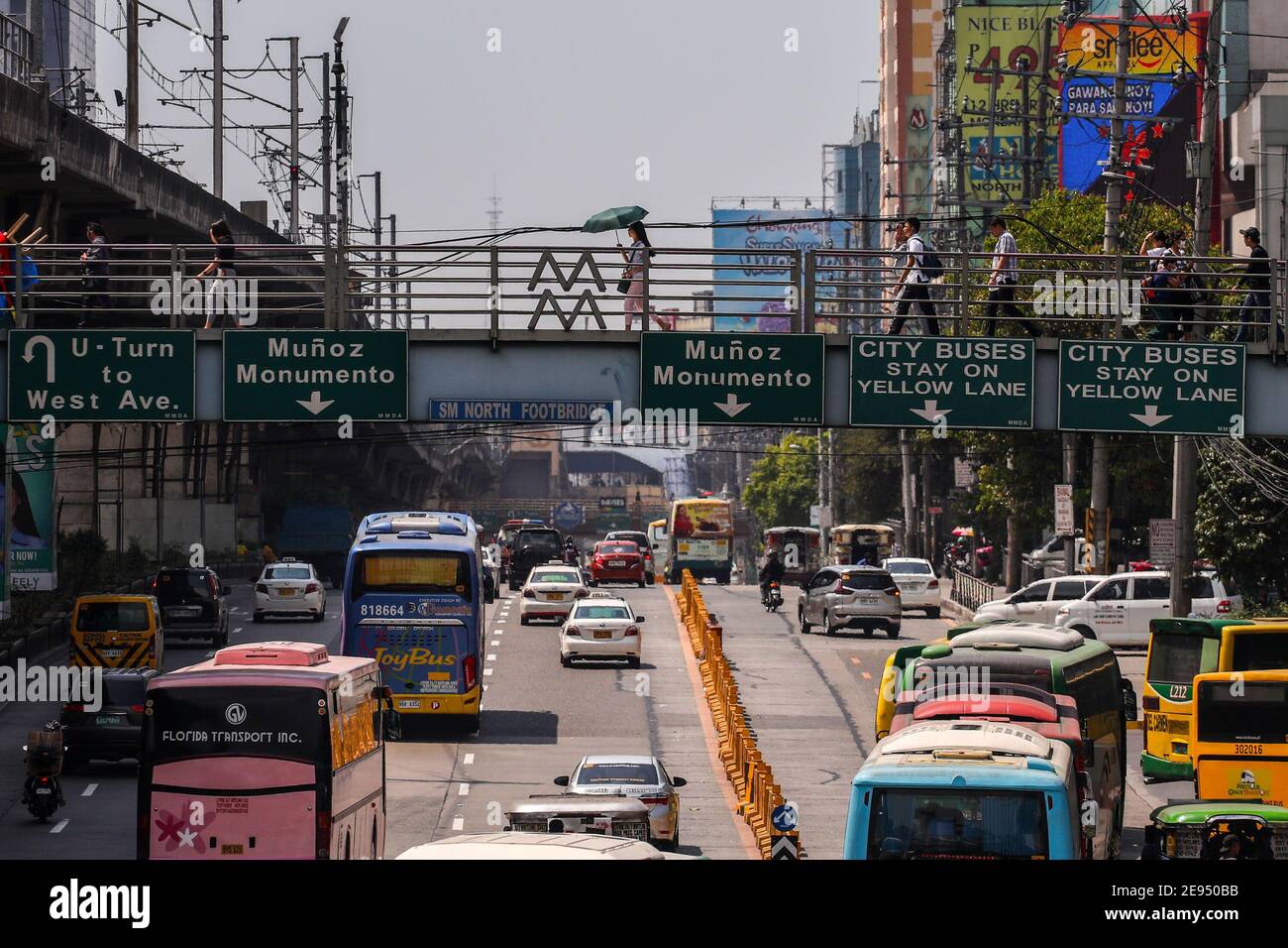 People walk on a pedestrian bridge along a major road. The Philippine ...