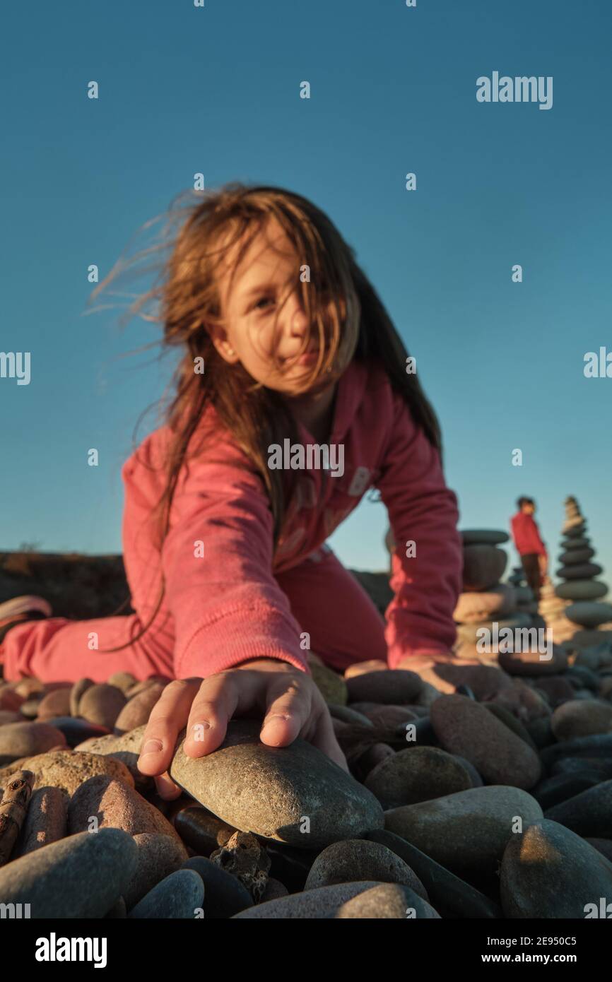 a girl builds a pyramid of stones on the beach Stock Photo - Alamy