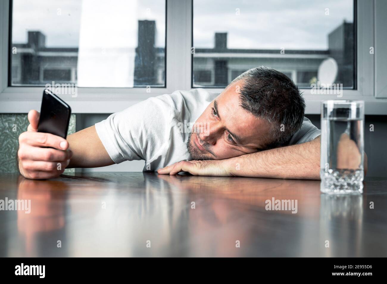 Young man bored using his smartphone. Bored young man sitting in his ...
