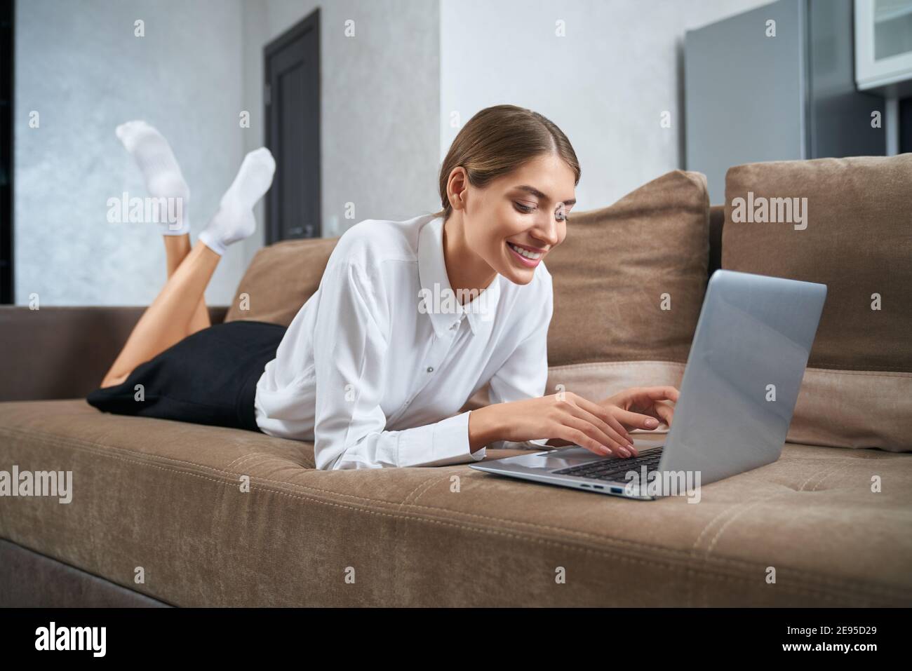 Pleasant woman in white shirt and black skirt lying on comfortable ...