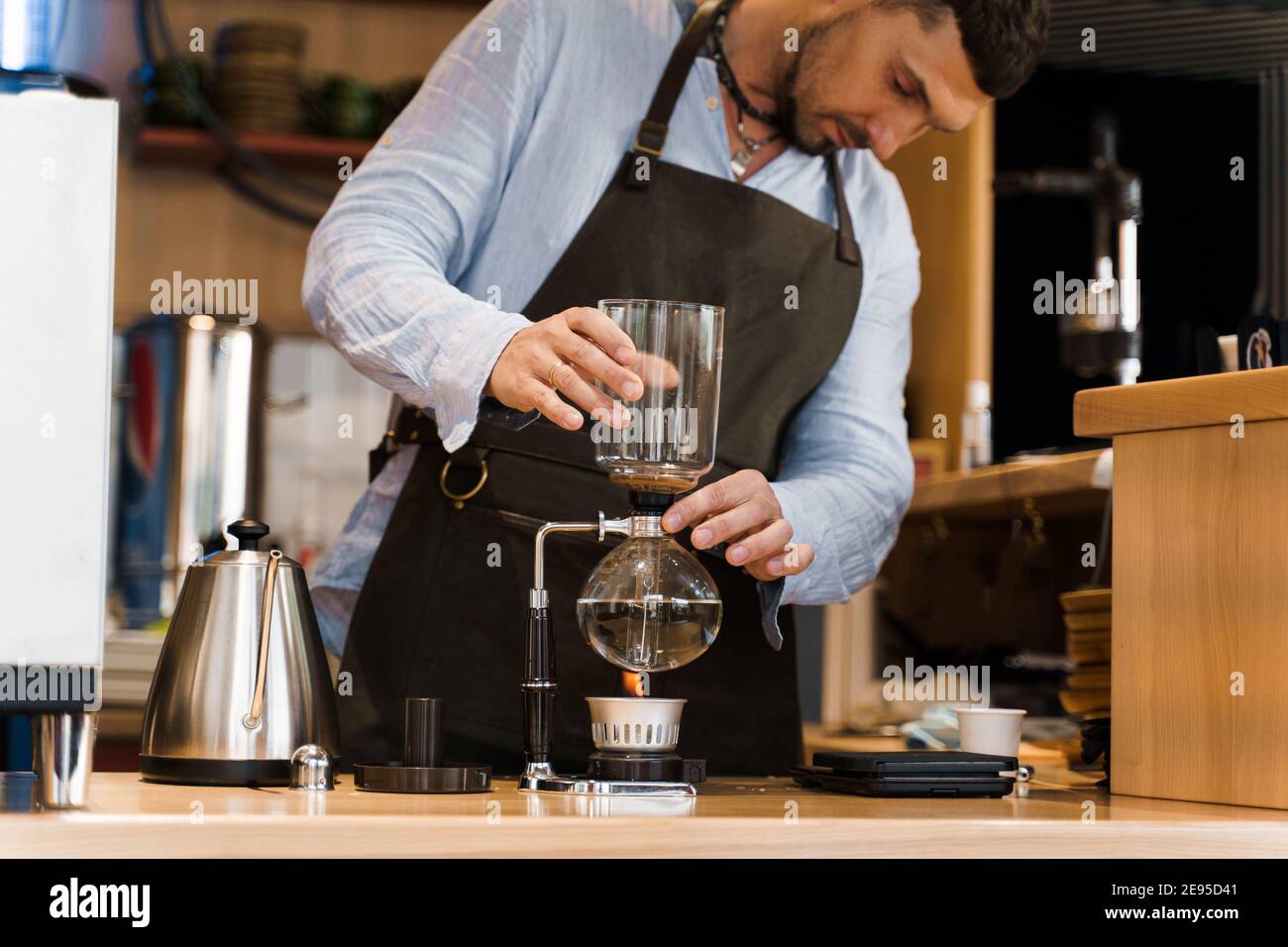 Handsome bearded barista holds Syphon device in hands before coffee ...
