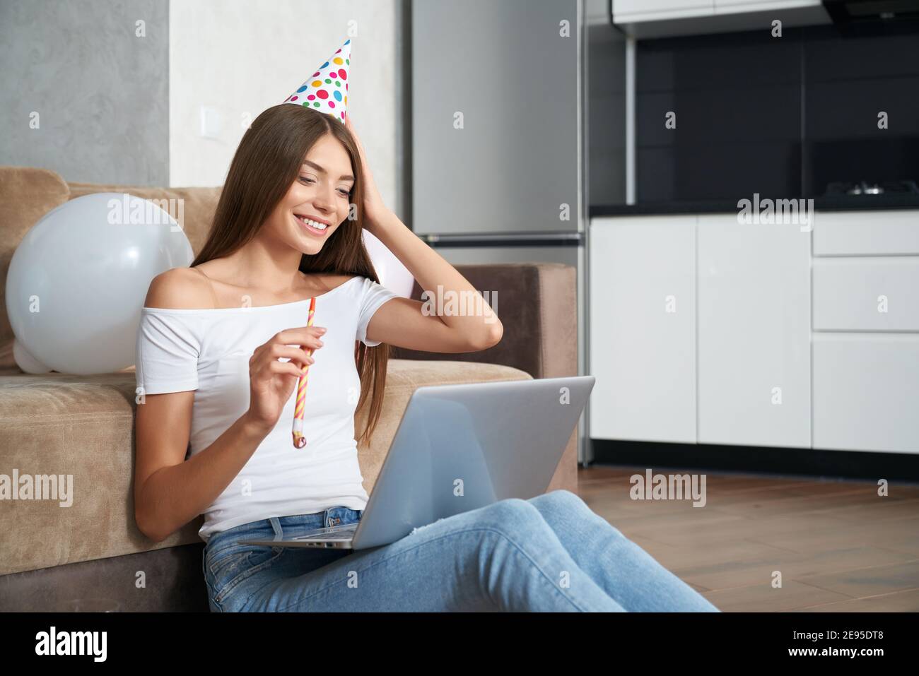 Smiling beautiful woman in party hat sitting on floor with opened ...