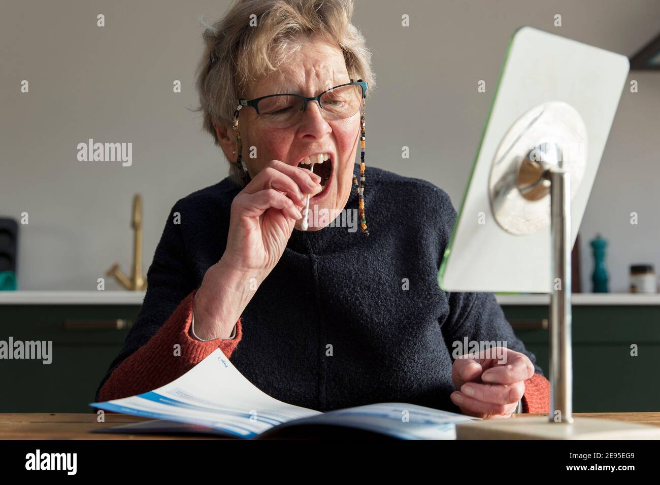 A senior woman takes a mouth sawb at home to check for coronavirus ...