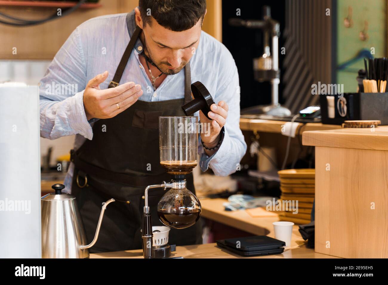 Barista sniffs flavored coffee in syphon device. Barista checks coffee ...