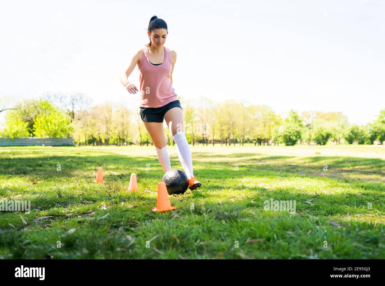 Portrait of young female soccer player running around cones while ...