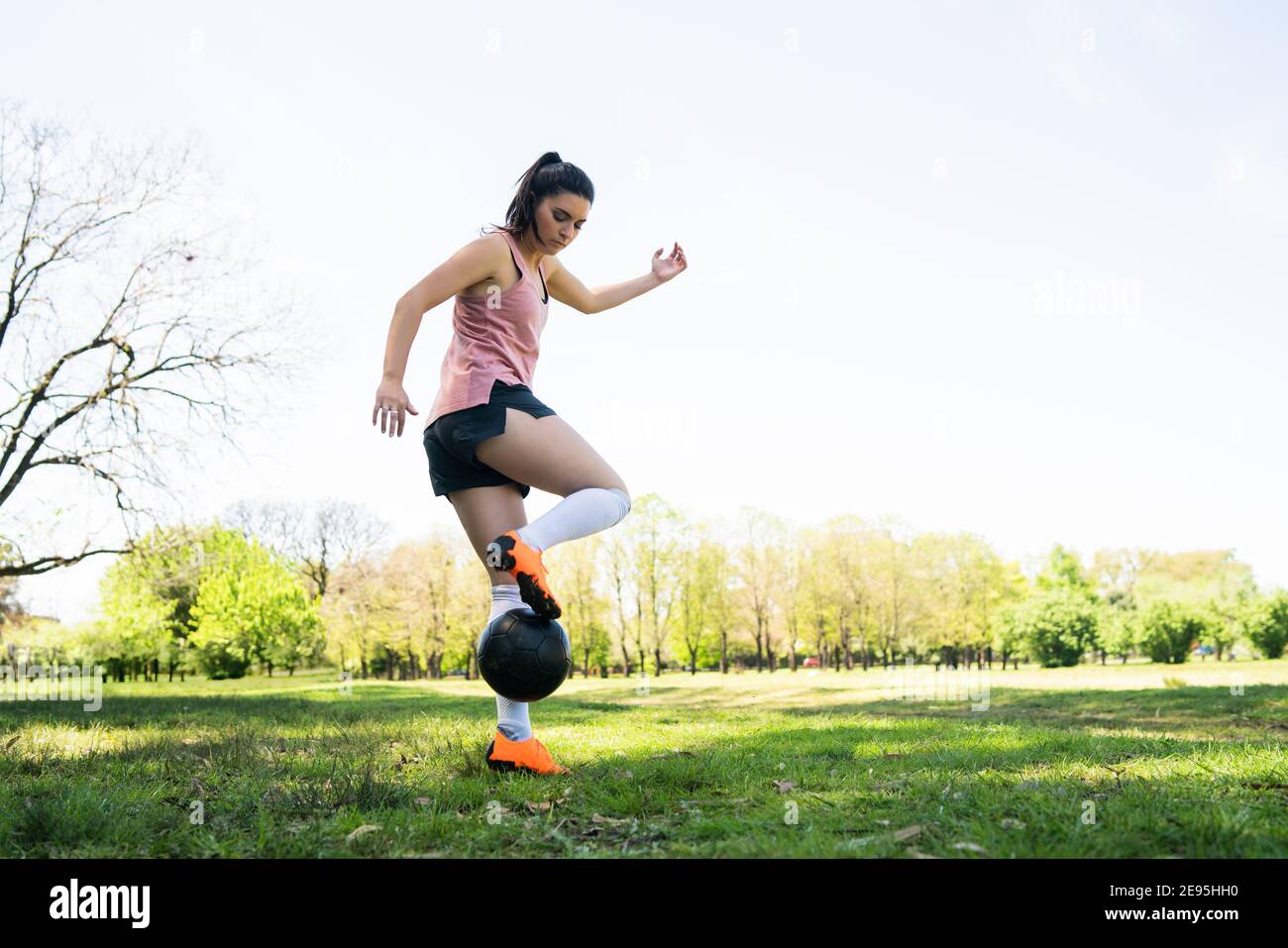 Portrait of young female soccer player running around cones while ...