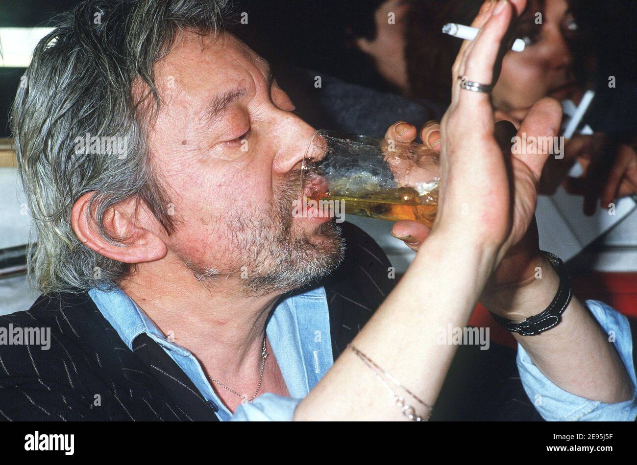 French singer Serge Gainsbourg smoking and drinking whisky in a pub ...