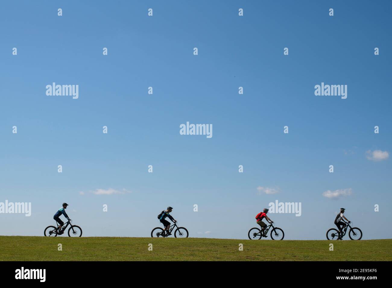 Three men ride mountain bikes along the grass near North Nibley in ...