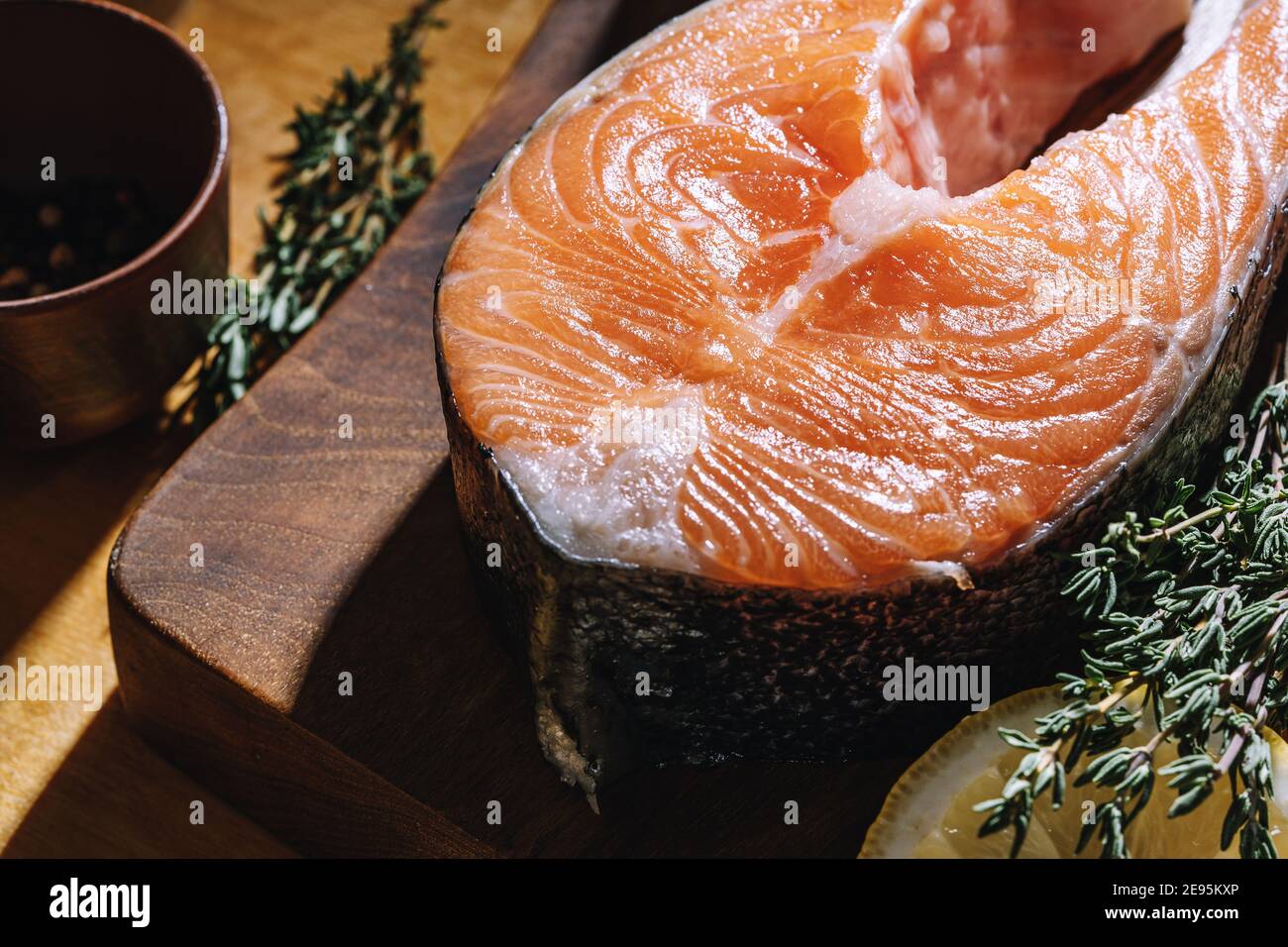 Raw salmon steak with lemon and thyme on wooden board, top view. Harsh ...