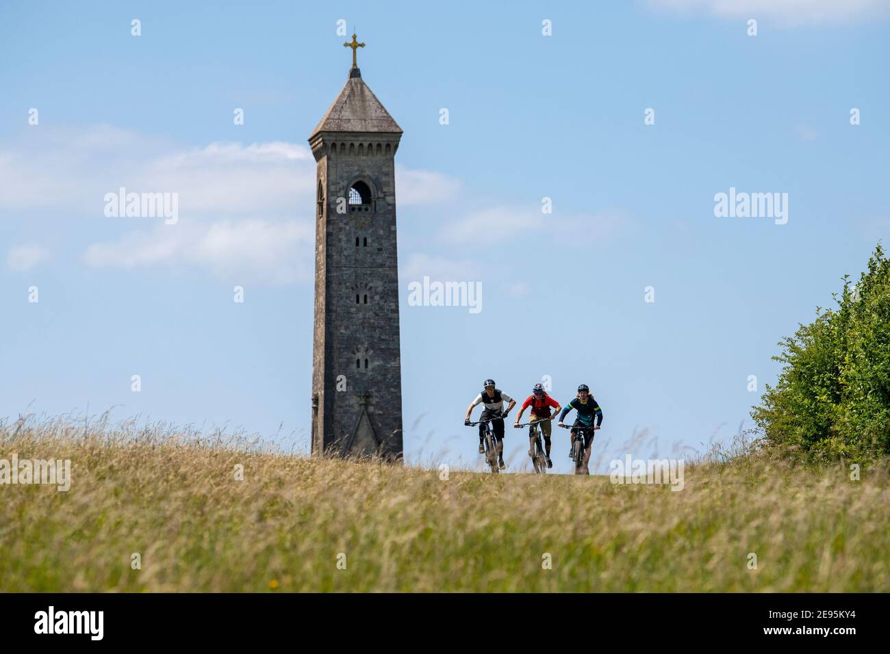 Three men ride mountain bikes past the Tyndale Monument, a tower built ...