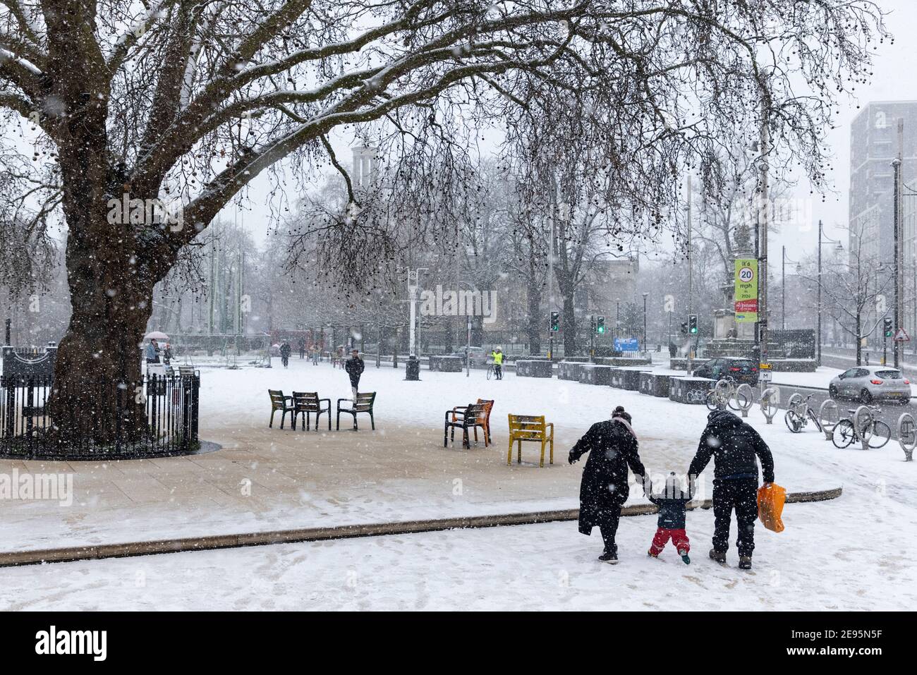Parents hold the hands of their toddler during heavy snow, Windrush ...