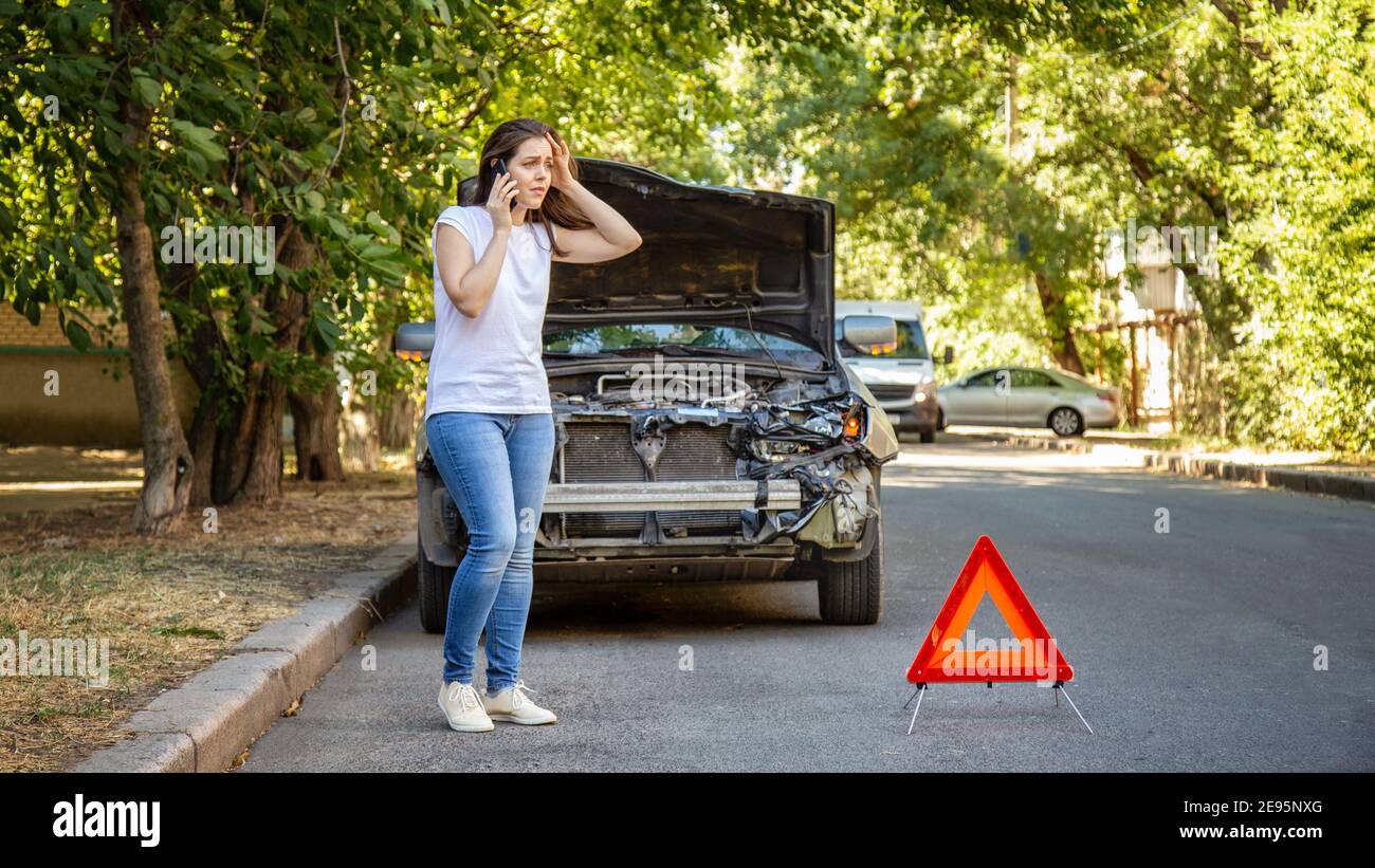 Driver woman in front of wrecked car in car accident. Scared woman in ...