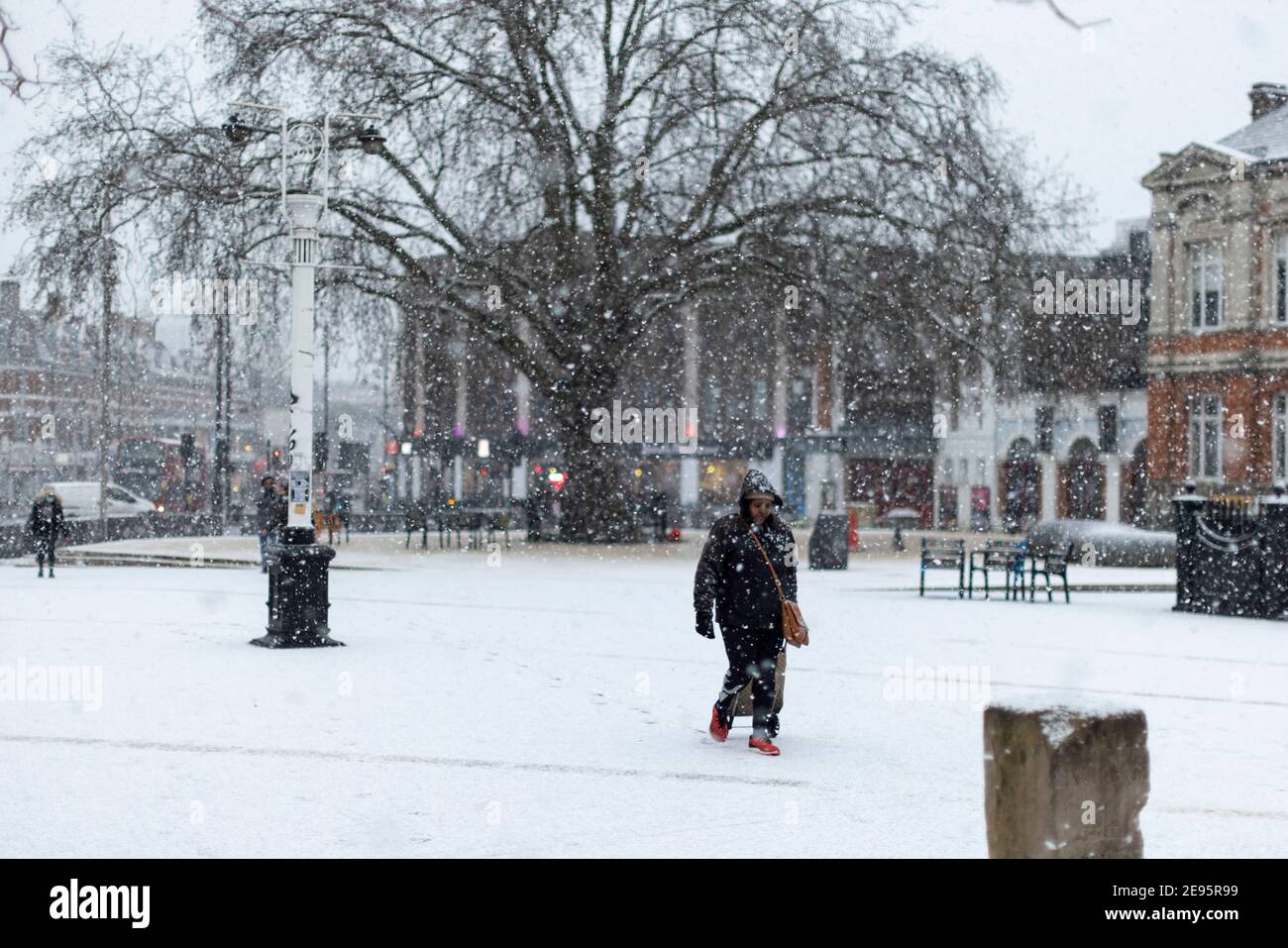 A woman walks across Windrush Square during heavy snow, Brixton, London ...
