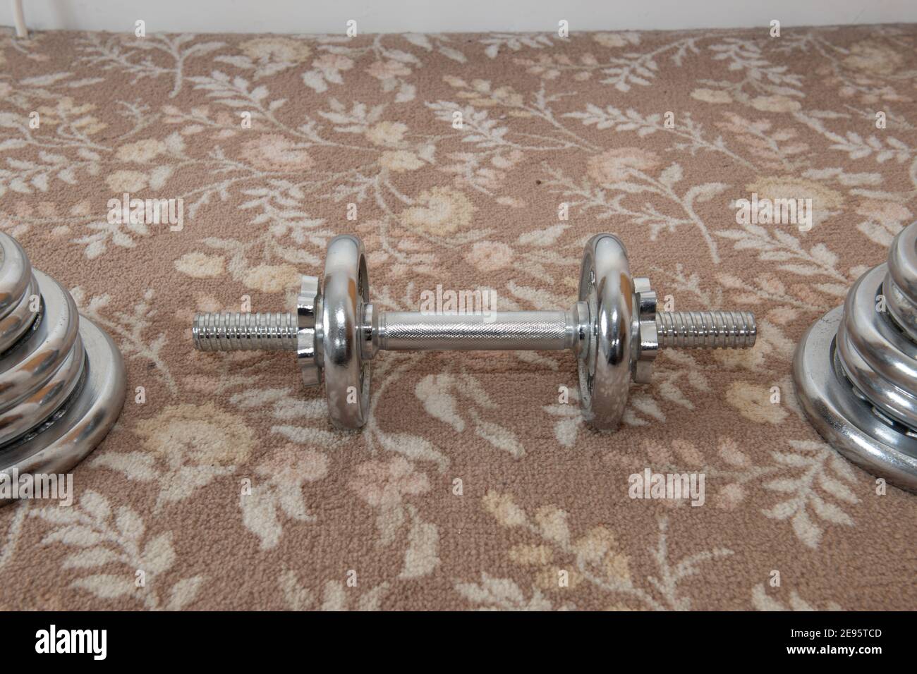 Close up of a small dumbbell on the floor in between a heap of heavier ...