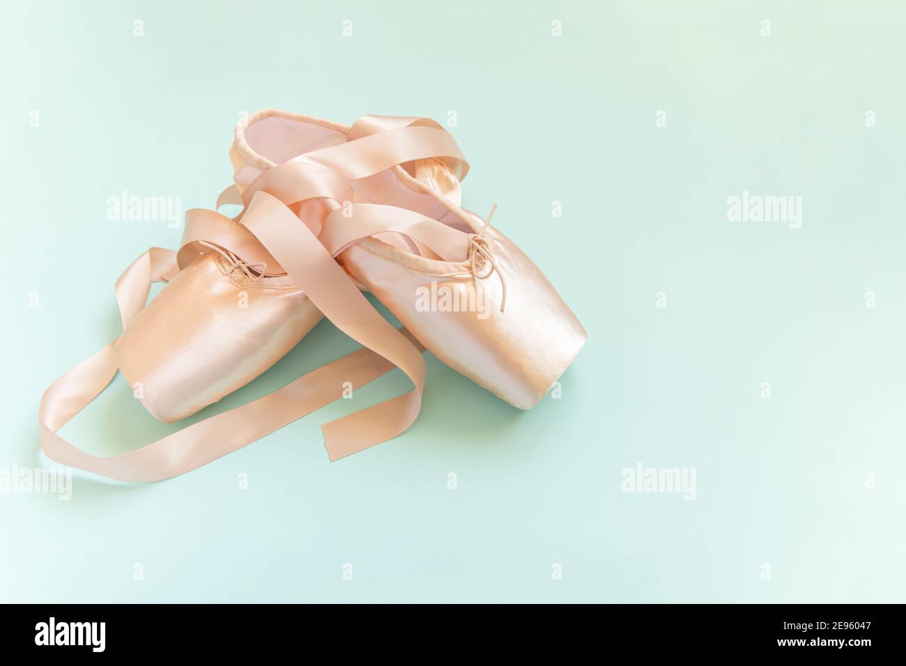 New pastel beige ballet shoes with satin ribbon isolated on blue ...