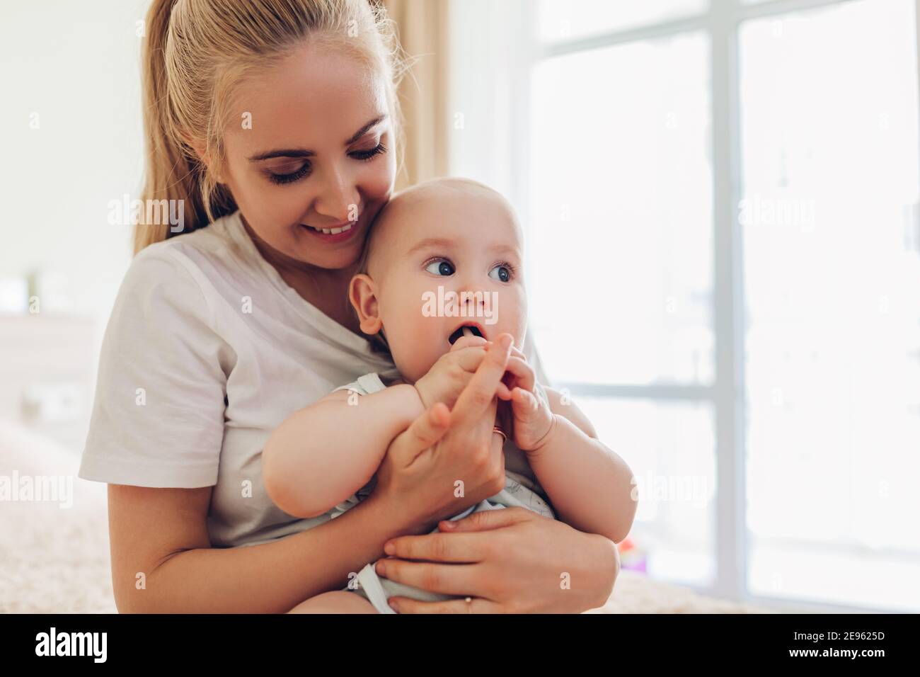Mother playing with her newborn baby son at home. Family having fun ...