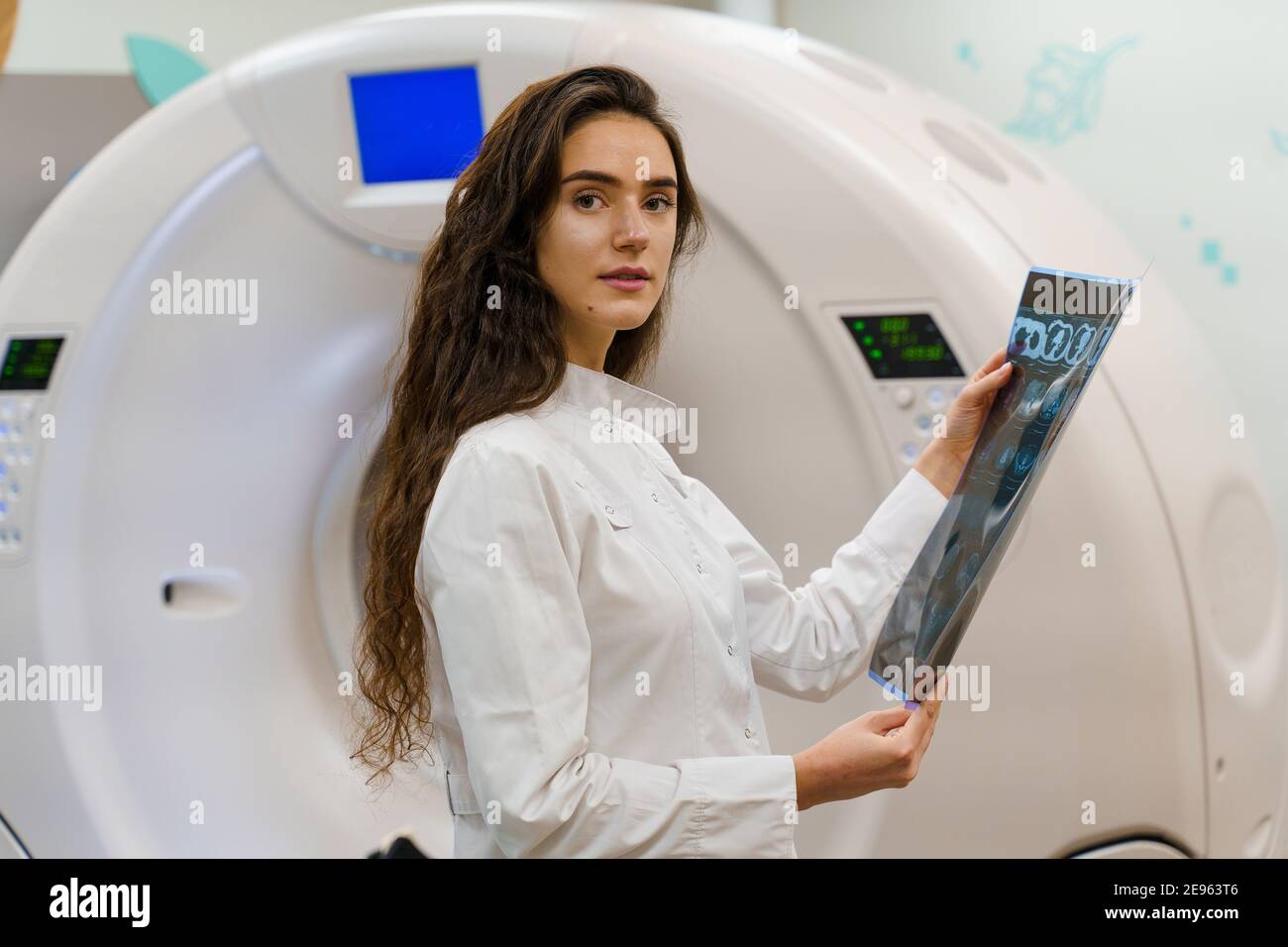 The young women doctor in medical gown looks in camera. Girl with x-ray ...