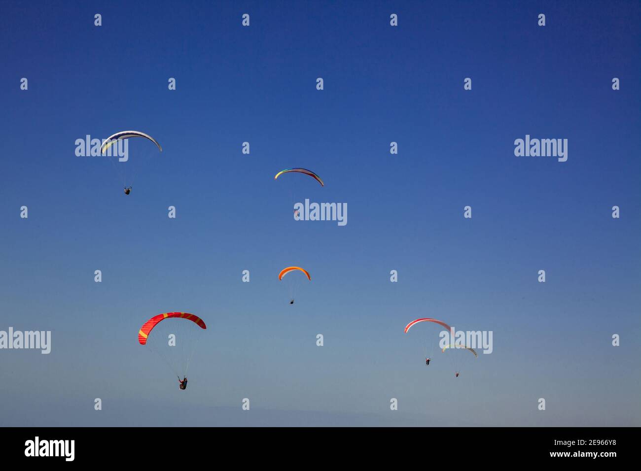 Blue and red paragliding parachute on light blue sky with copy space ...