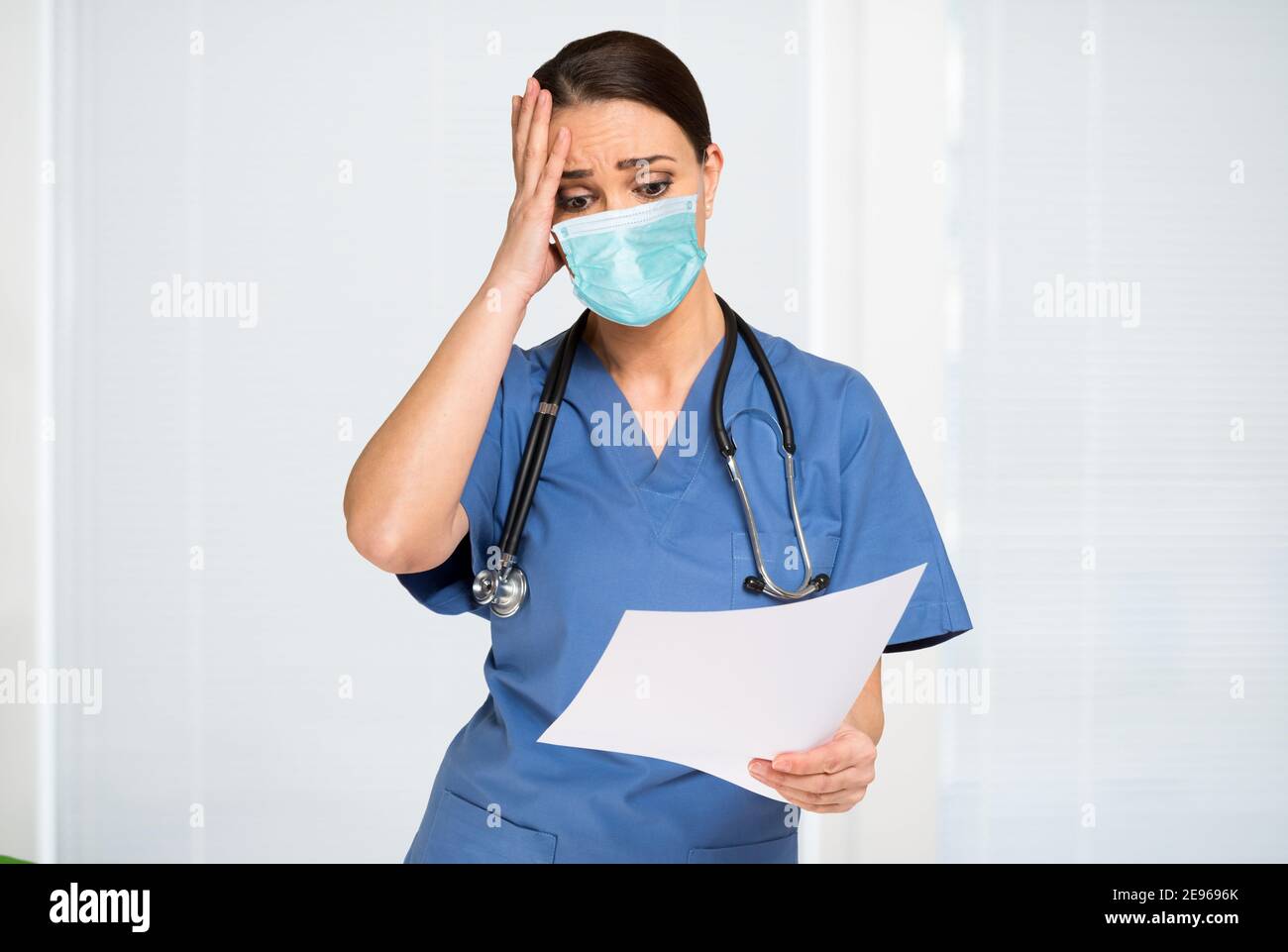 Masked nurse reading a document in the hospital, covid coronavirus ...