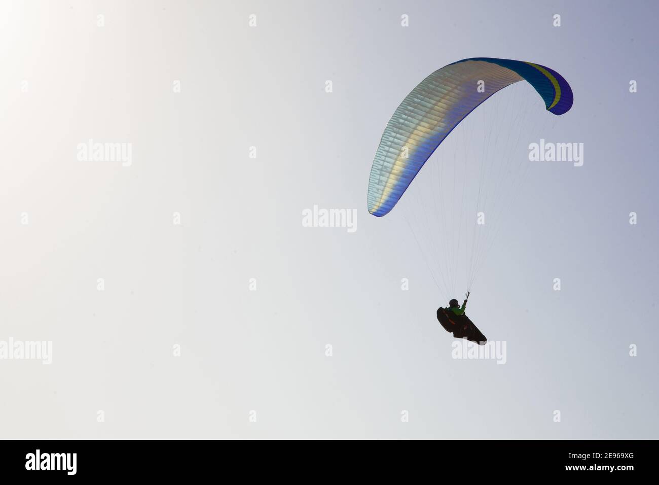 Blue and red paragliding parachute on light blue sky with copy space ...