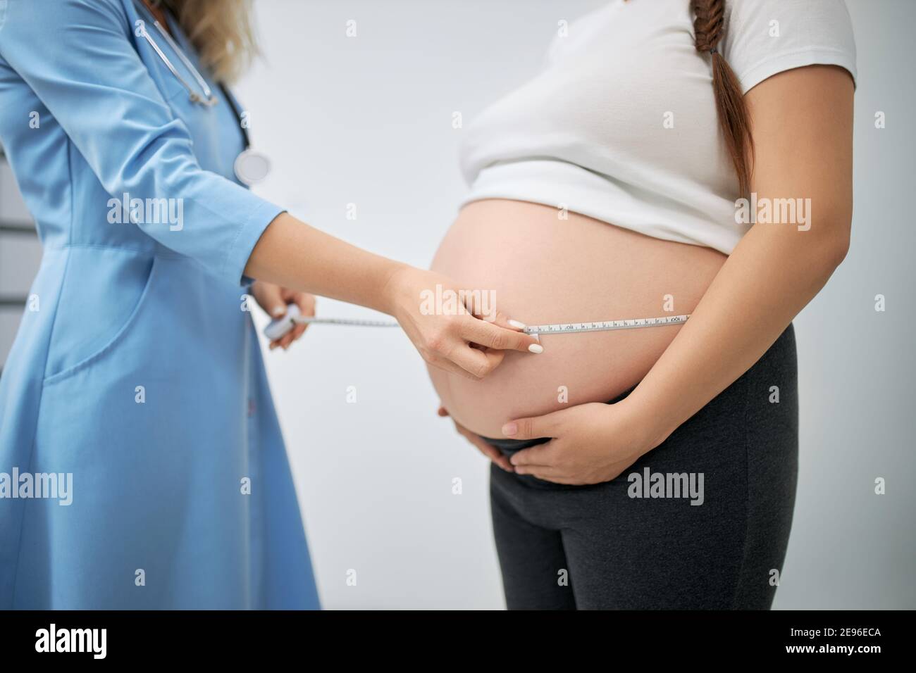 Qualified doctor measuring pregnant woman's belly with tape at modern ...