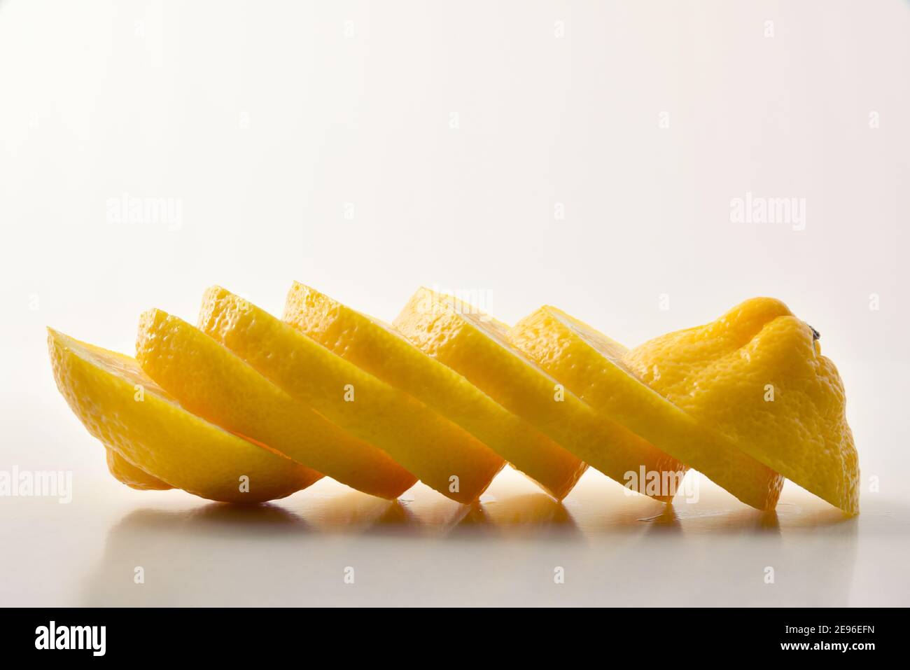 Detail of lemon cut into slices on a white table and white isolated ...
