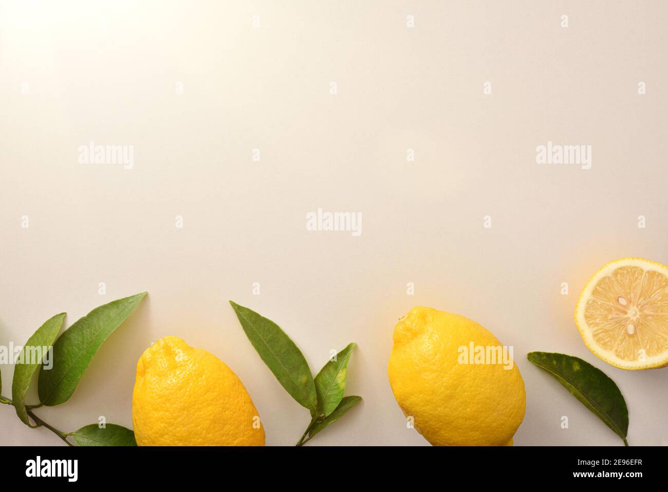 Group of lemons with leaves and half lemon on white table. Top view ...