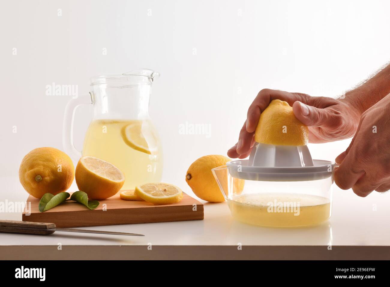 Hands squeezing a lemon in a plastic juicer with container for ...