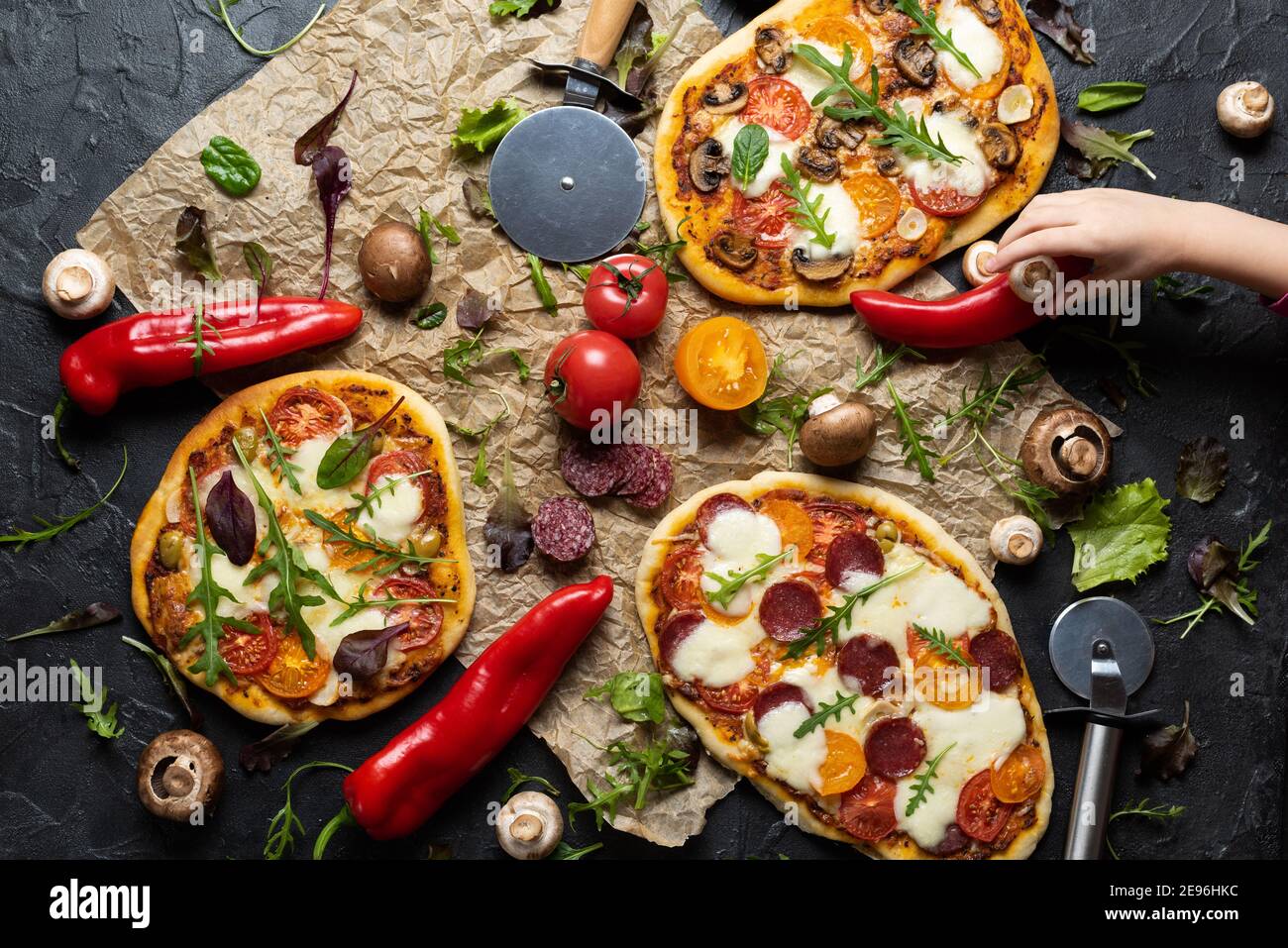 Three pizzas with child hand overhead view Stock Photo - Alamy