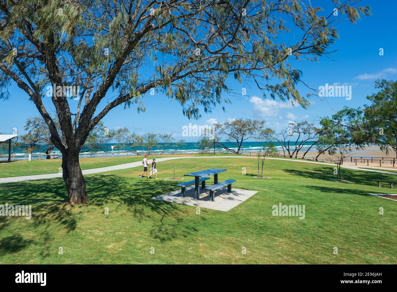 Two people walking along the waterfront at Elliott Heads, near ...
