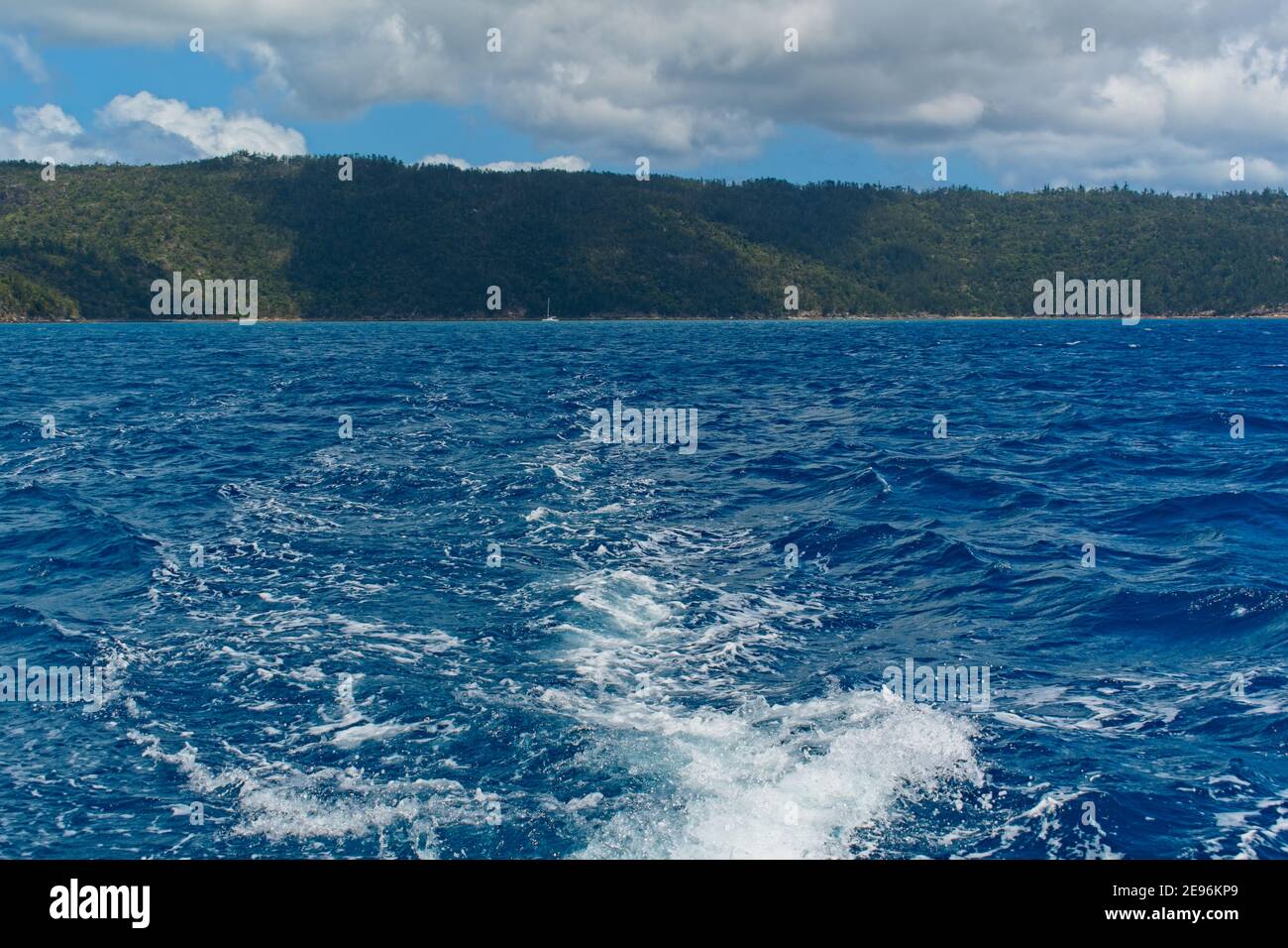 Ocean wake in blue water with view to Hamilton Island Stock Photo - Alamy