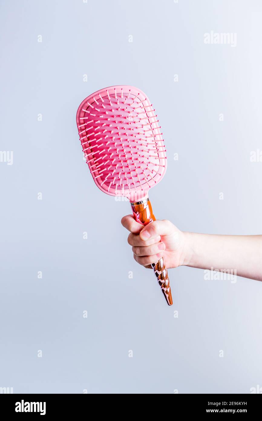 Beautiful pink comb brush in the hand of a girl on a white background ...