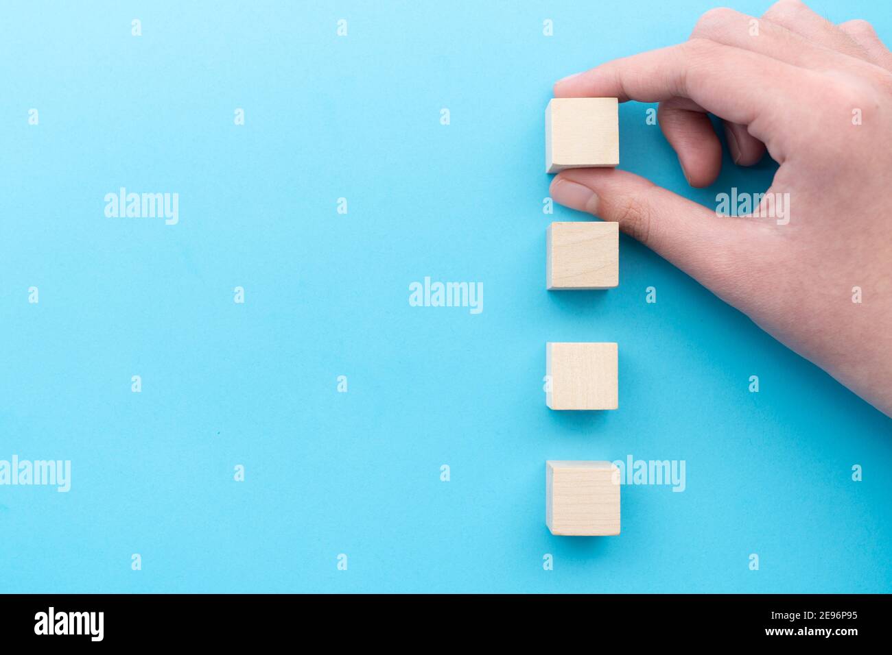 Hand holding a row of four blank wooden cubes Stock Photo - Alamy