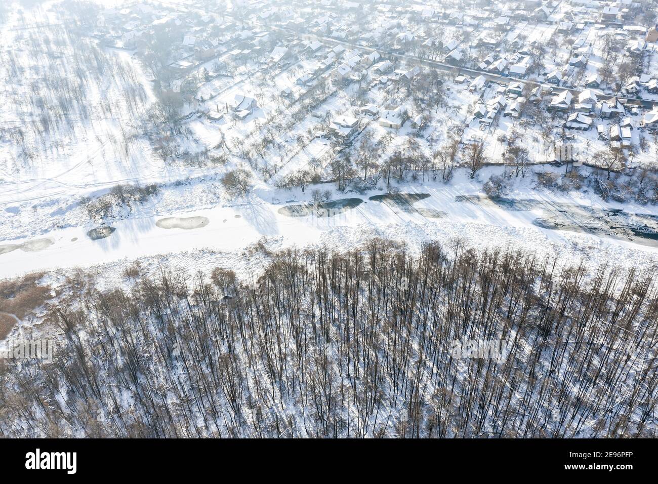 winter village landscape with snow-covered river and forest. aerial ...