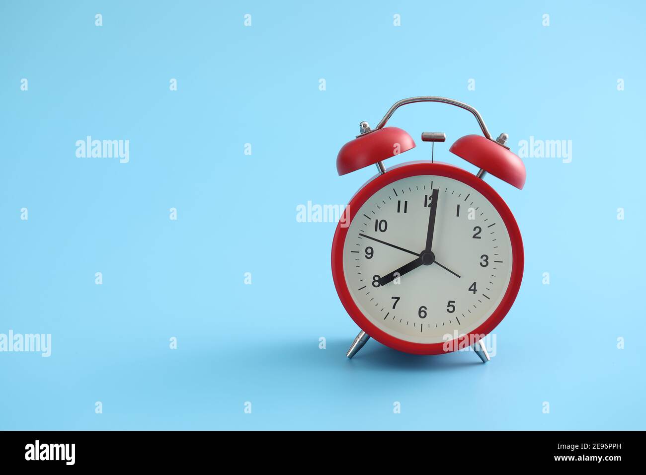 Red retro alarm clock isolated on a blue background Stock Photo - Alamy