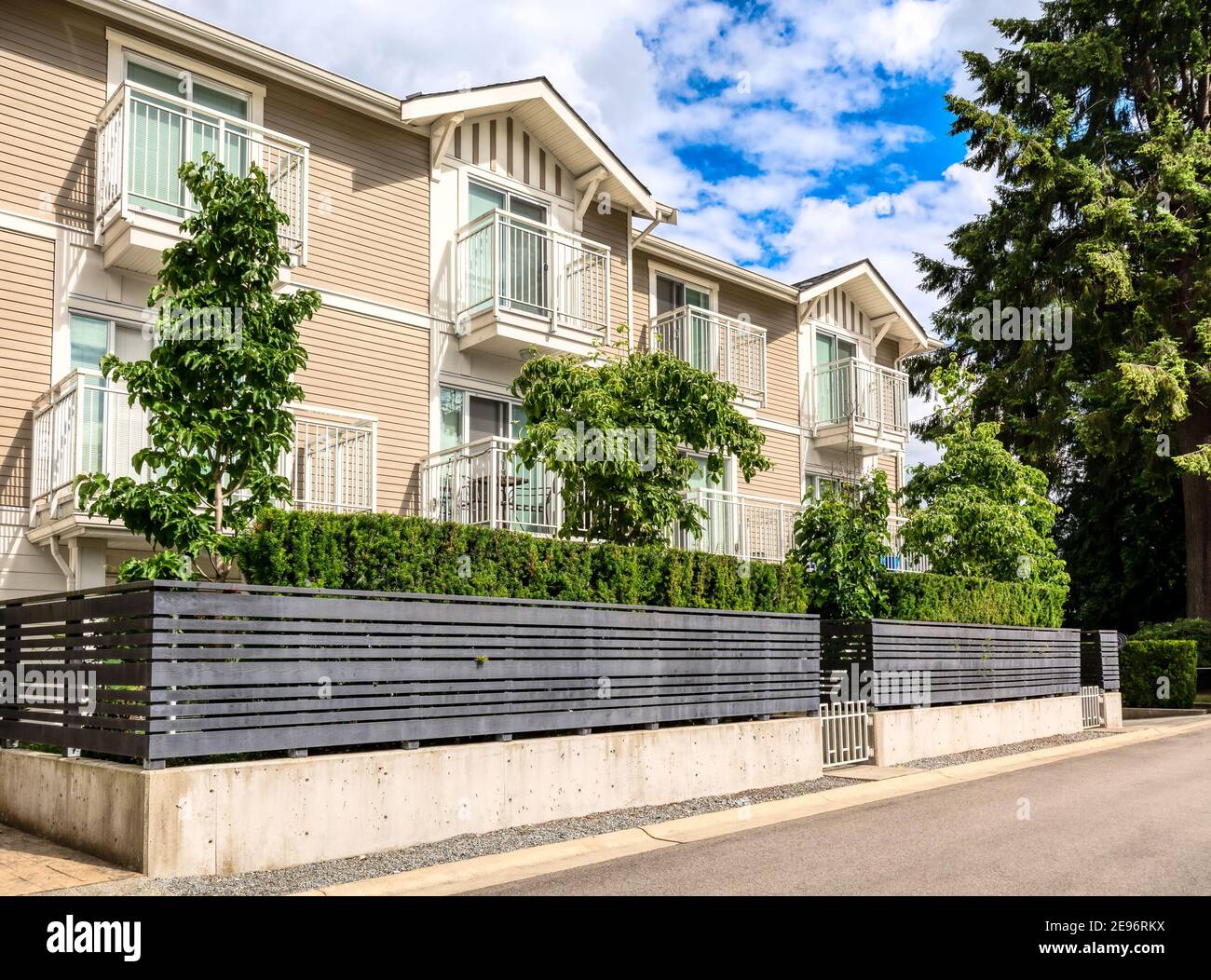 Residential condo building with fenced front yard on bright sunny day ...