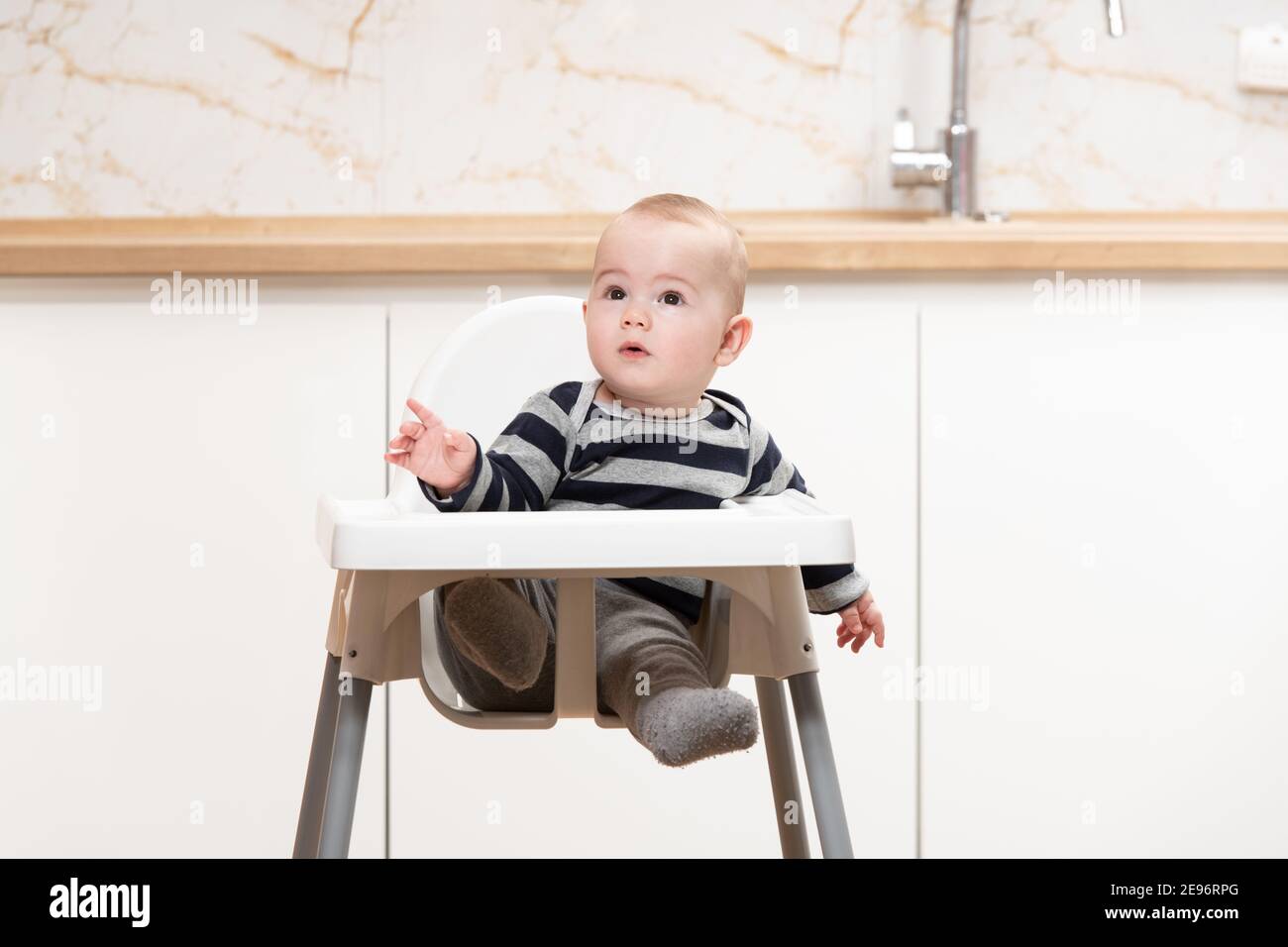 Happy Baby Sitting in High Chair in a White Kitchen Stock Photo - Alamy