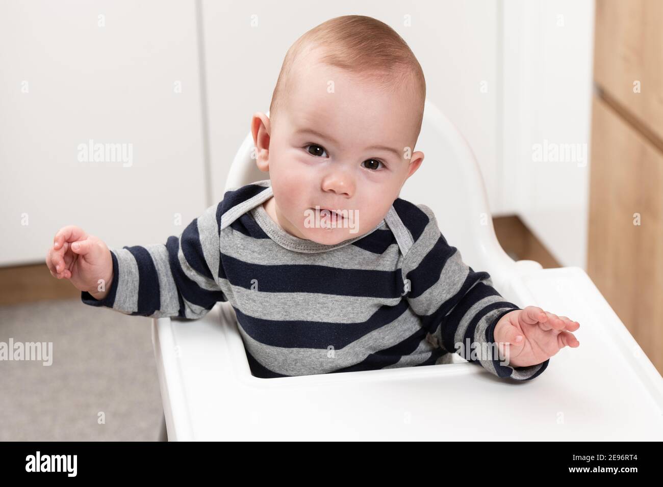 Happy Baby Sitting in High Chair in a White Kitchen Stock Photo - Alamy