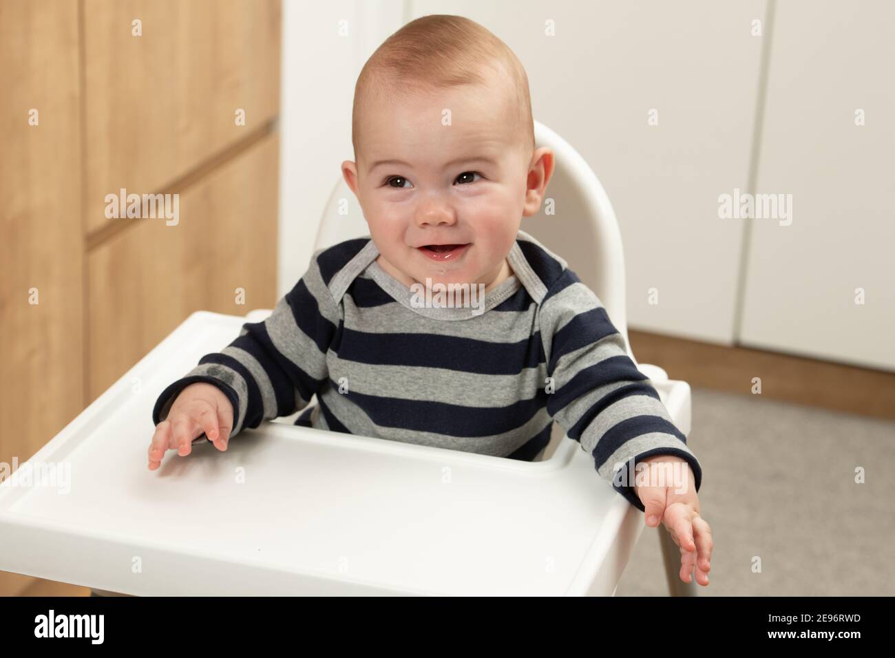 Happy Baby Sitting in High Chair in a White Kitchen Stock Photo - Alamy