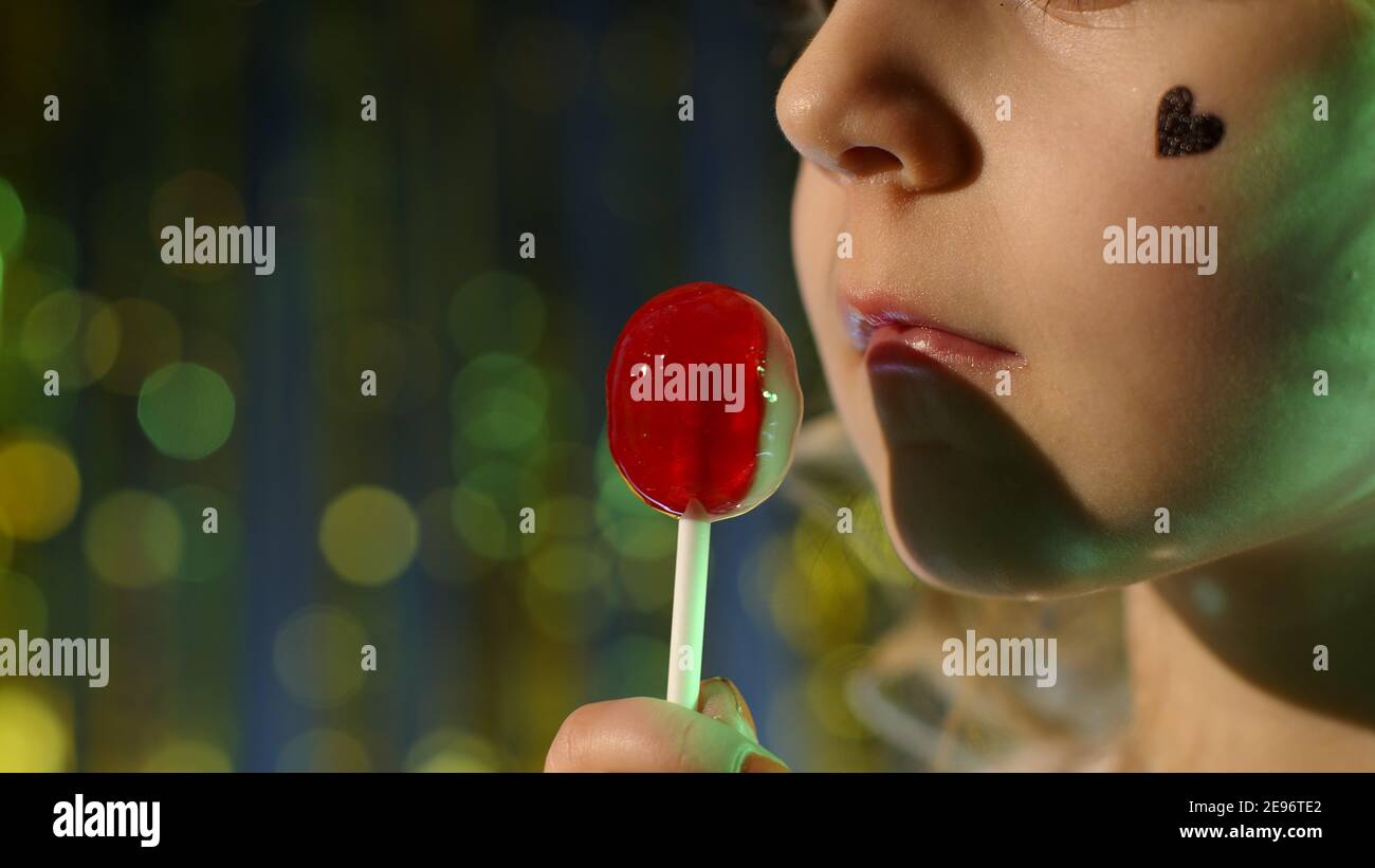 Close-up shot of futuristic hipster teen girl licking lollipop candy in ...