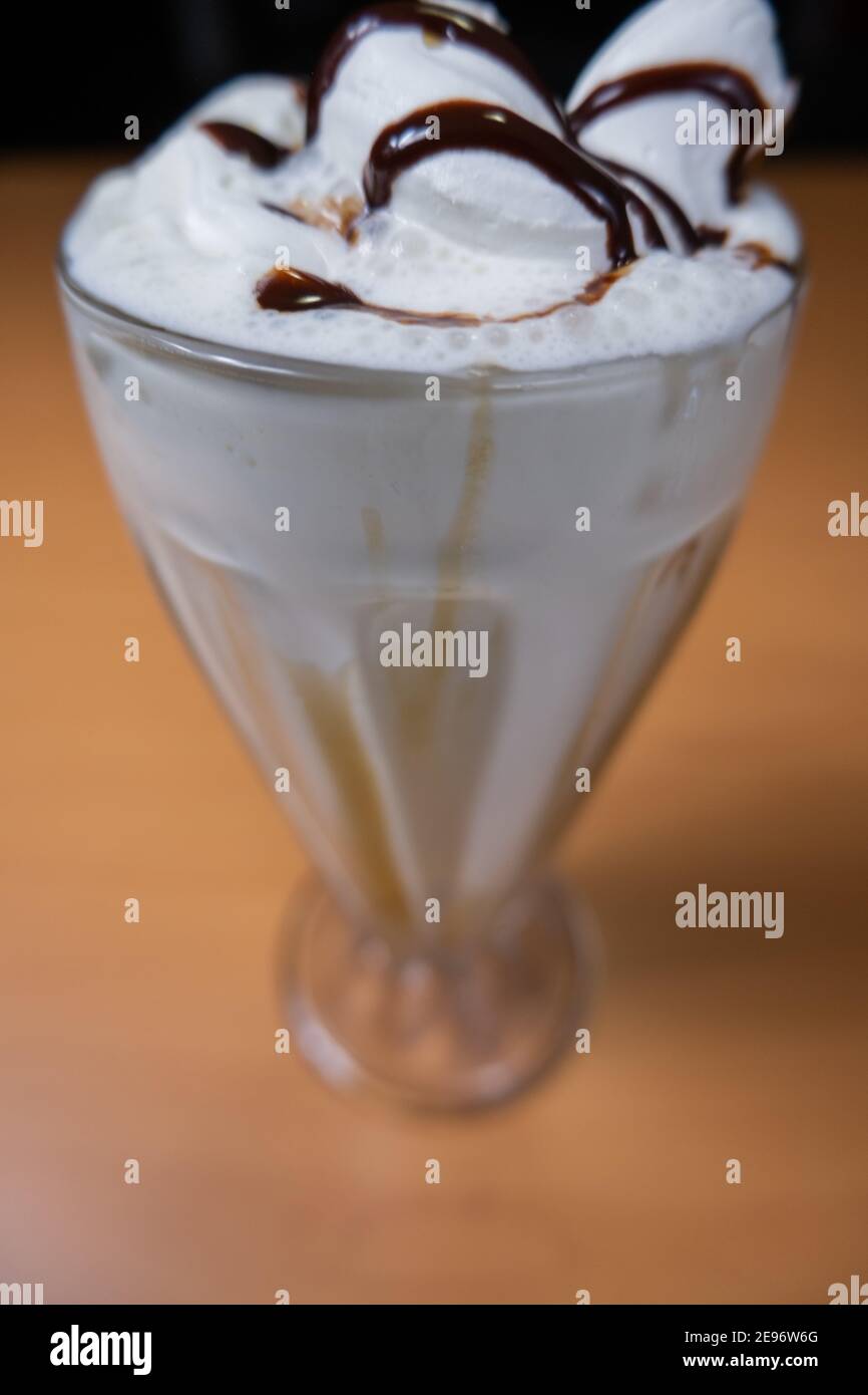 Vanilla milkshake with chocolate syrup on a table Stock Photo - Alamy