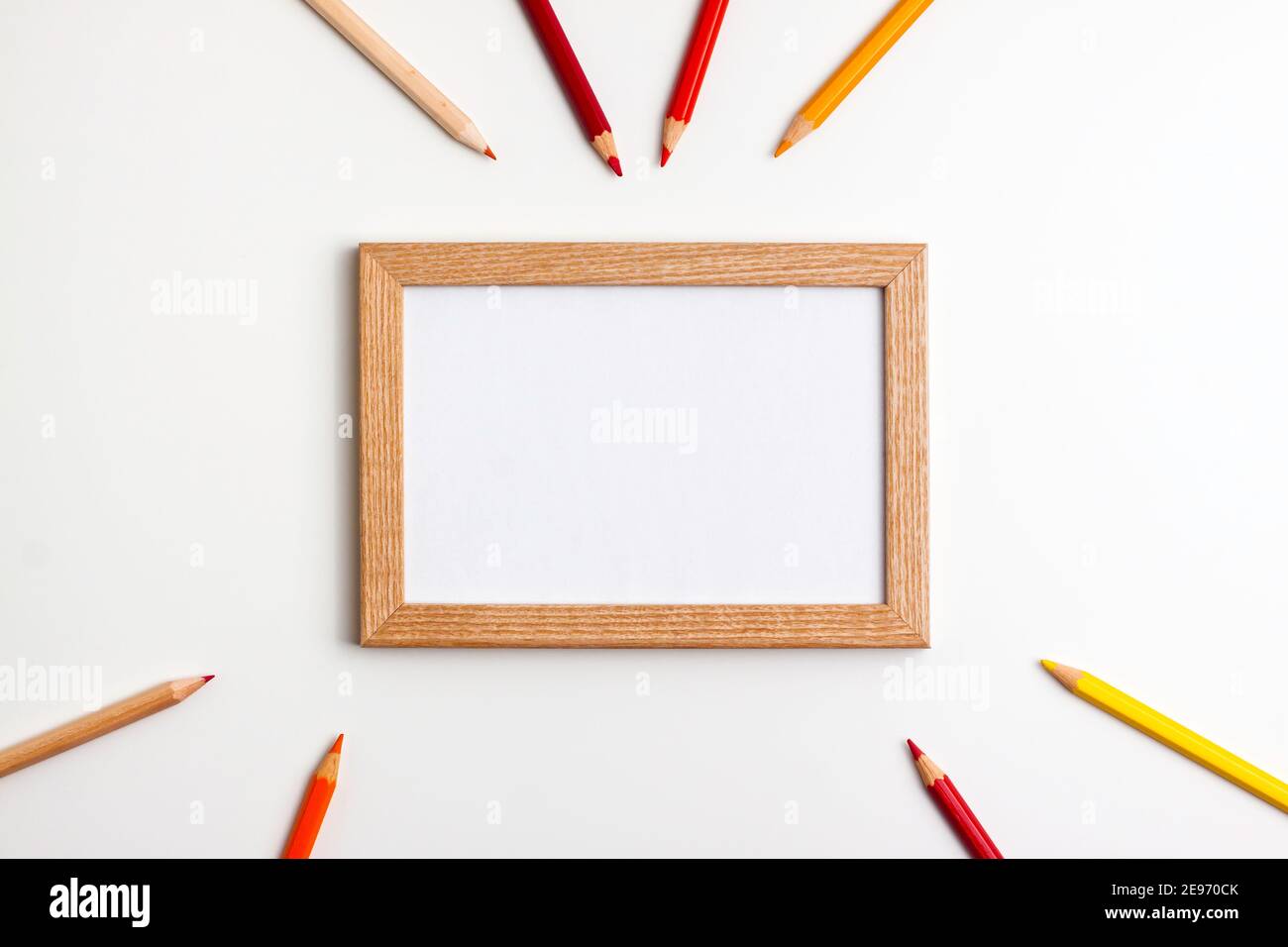 Yellow red pencils and wooden frame on white background. Flat lay top ...