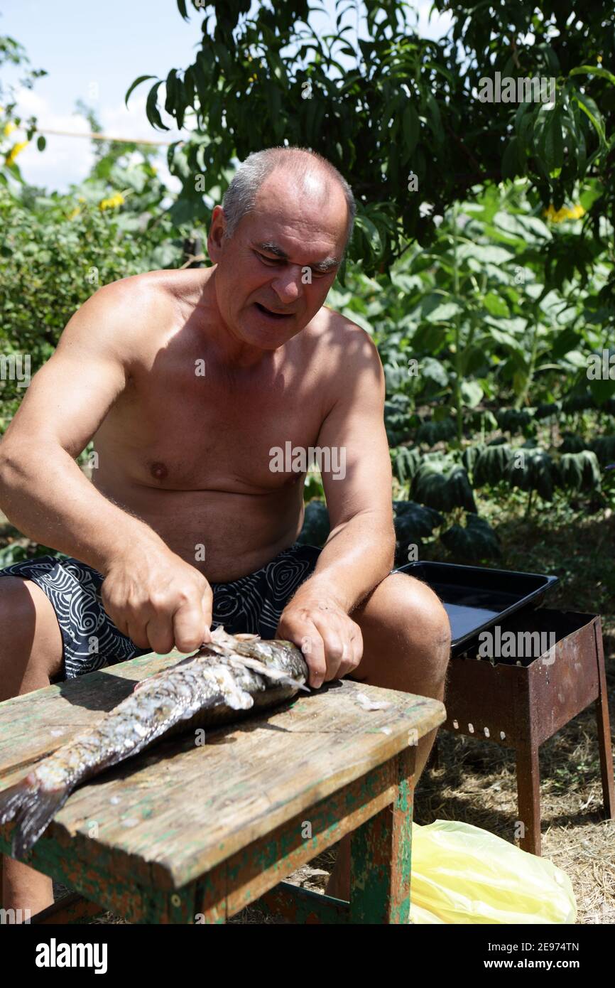 Man preparing a fish for cooking outdoor Stock Photo - Alamy