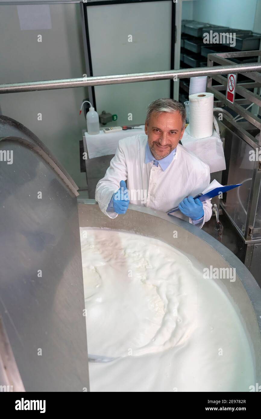 Food Engineer in White Uniform and Blue Gloves Looking at Camera. Milk ...