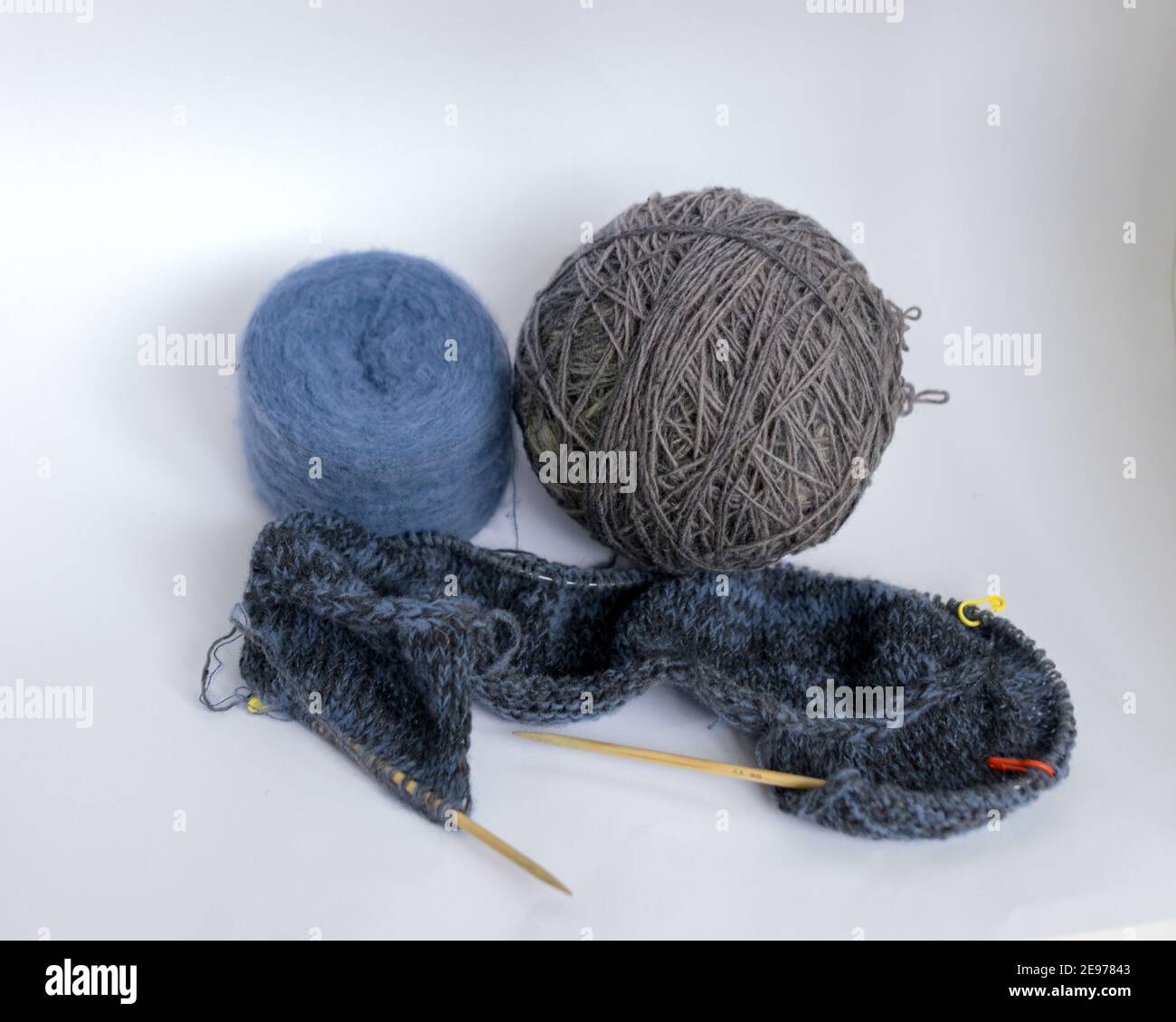 knitting from blue and gray yarn with wooden needles and blue balls of ...