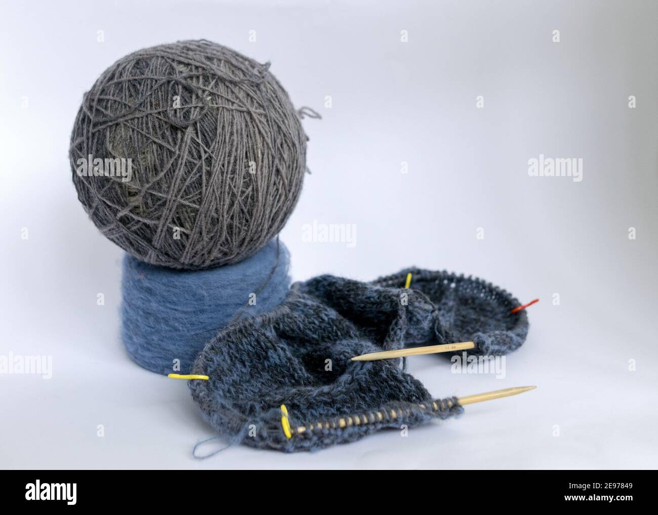 knitting from blue and gray yarn with wooden needles and blue balls of ...