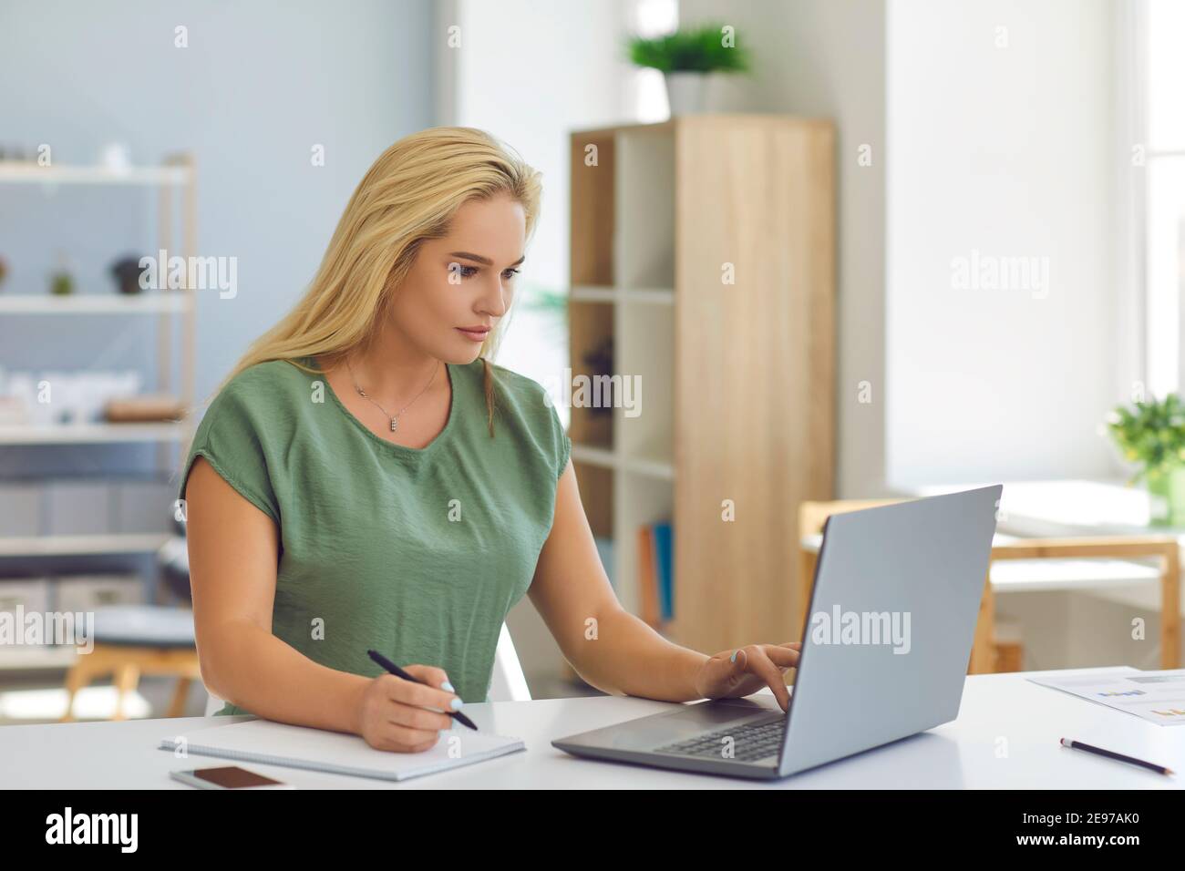 Woman sitting at desk with laptop, watching educational tutorial or ...