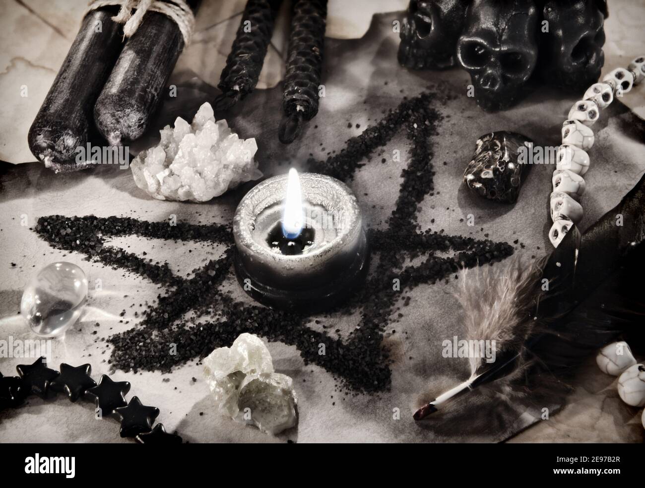 Pentagram symbol made of black salt with burning candle on old paper ...